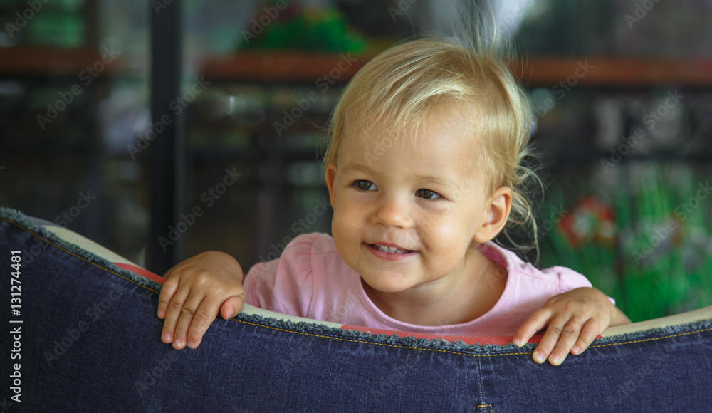 child sitting on the back of a large chair. Stock Photo | Adobe Stock