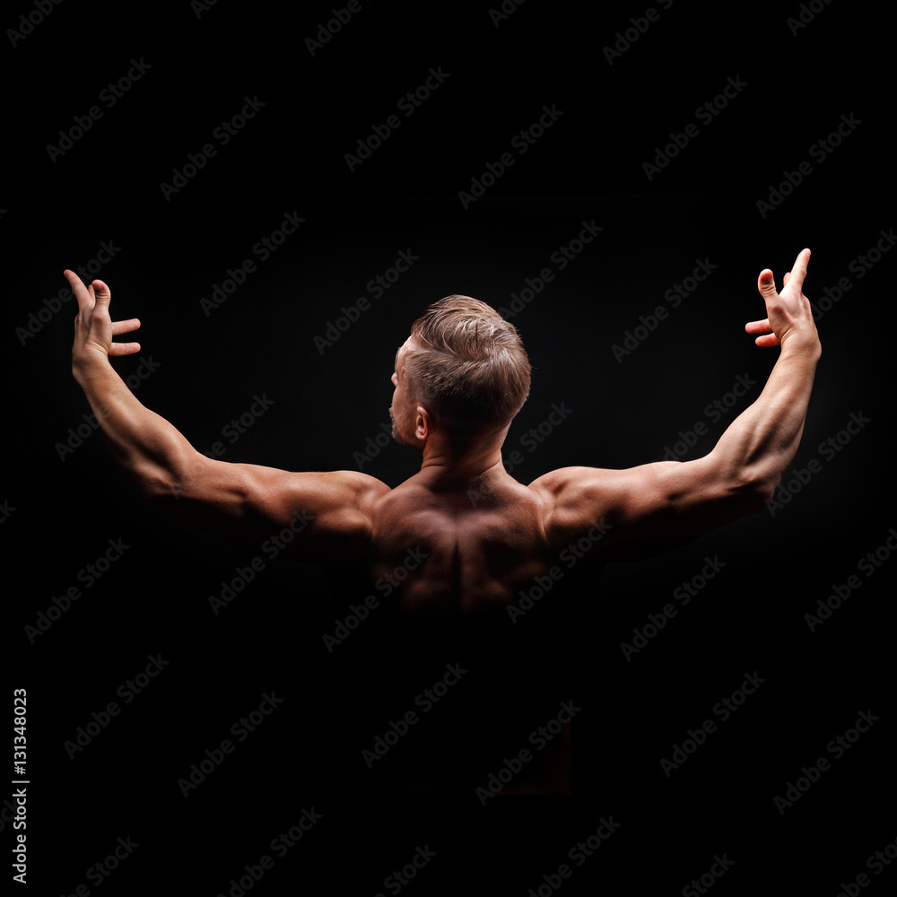 Bodybuilder posing on a black background. Dramatic portrait of an ...
