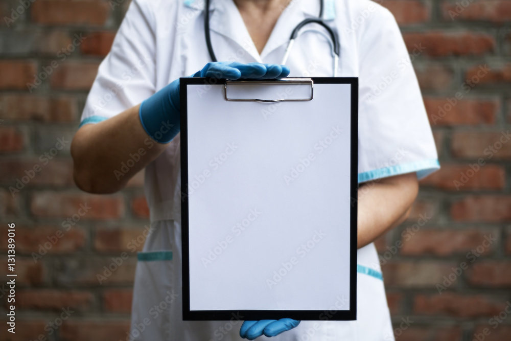 Female doctor's hand holding medical clipboard with blank sheet of ...