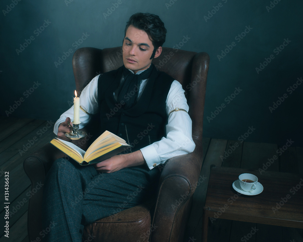 Foto de Retro victorian dickens style man reading book by candlelight ...