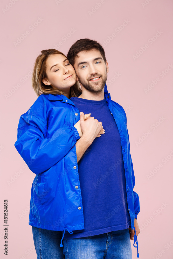 Funny young beautiful couple wearing one jacket embracing smiling over ...