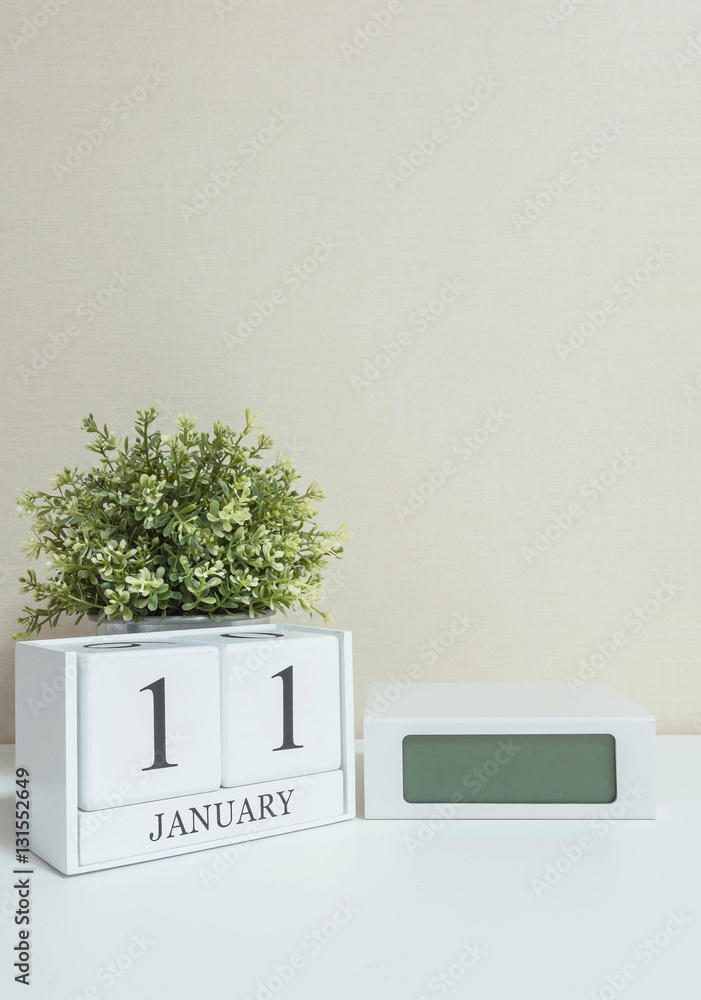 White wooden calendar with black 11 january word with clock and plant ...