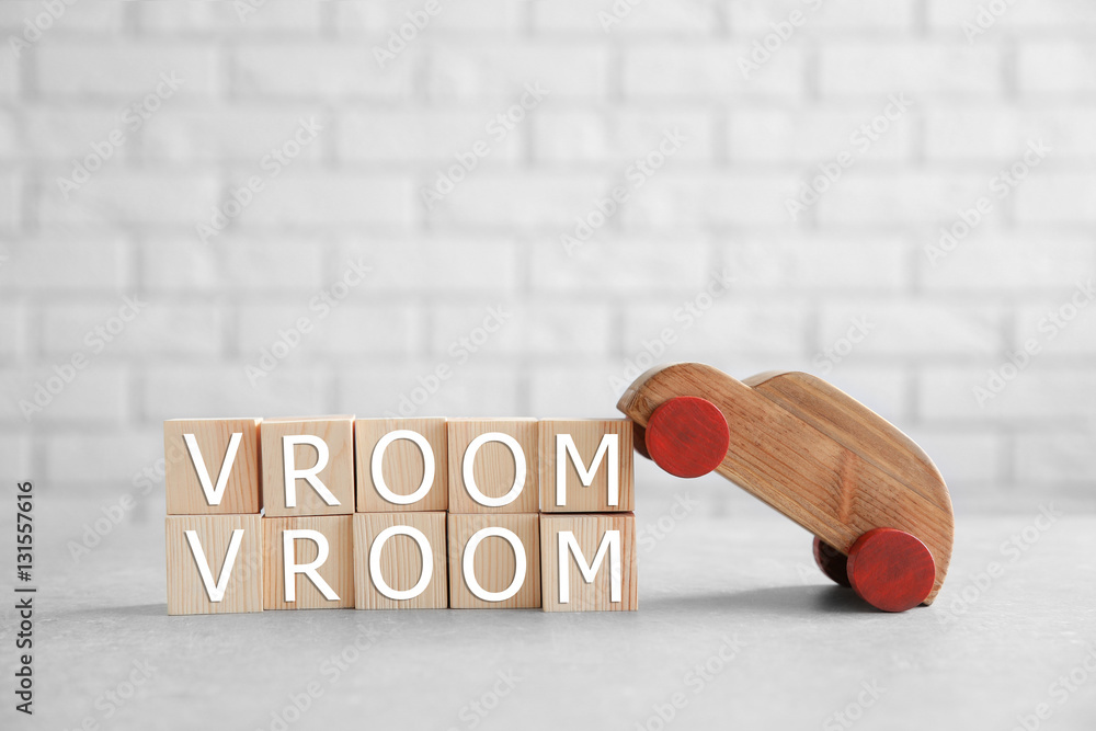 Cubes with words VROOM VROOM and toy car on brick wall background Stock ...