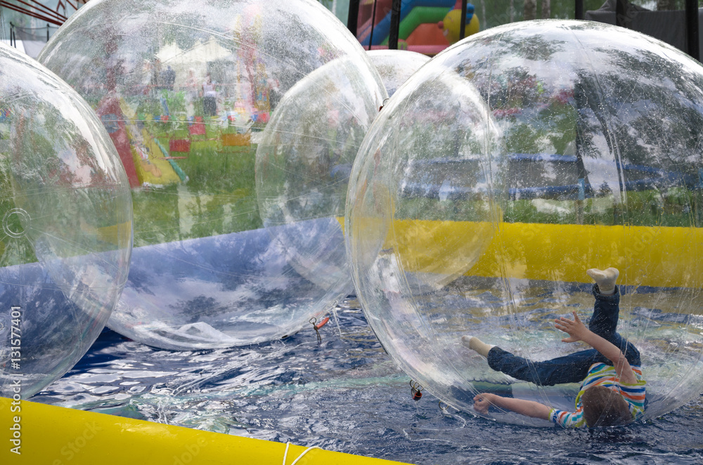 Boy riding in a zorb in the pool. Zorbing in an inflatable pool. Four ...