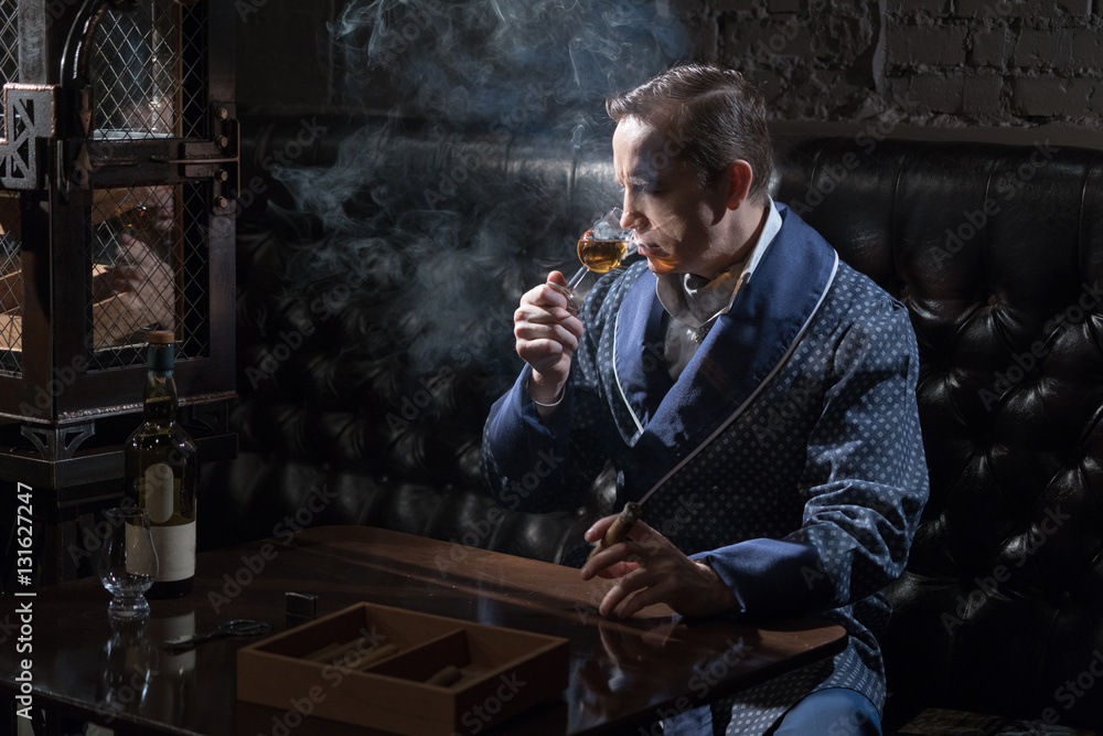 Man in an elegant dressing gown smoking a Cuban cigar and drinking ...