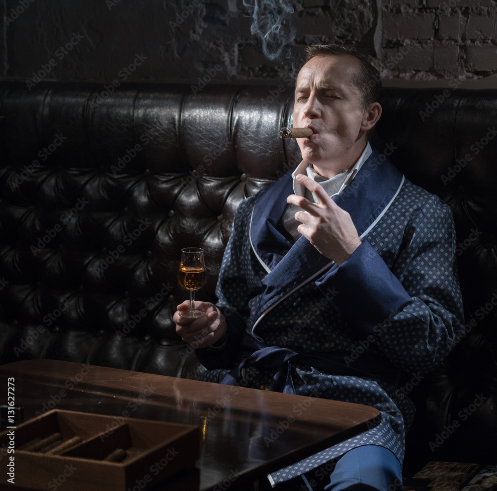 Man in an elegant dressing gown smoking a Cuban cigar and drinking ...