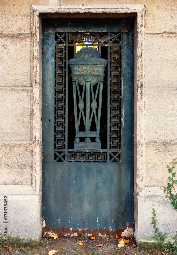 Weathered and rusty blue closed iron door of a crypt at a graveyard ...