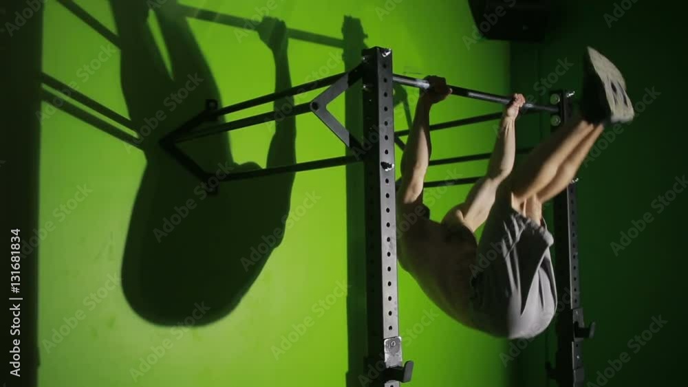 Shirtless man doing stomach exercises on a horizontal bar. CrossFit ...