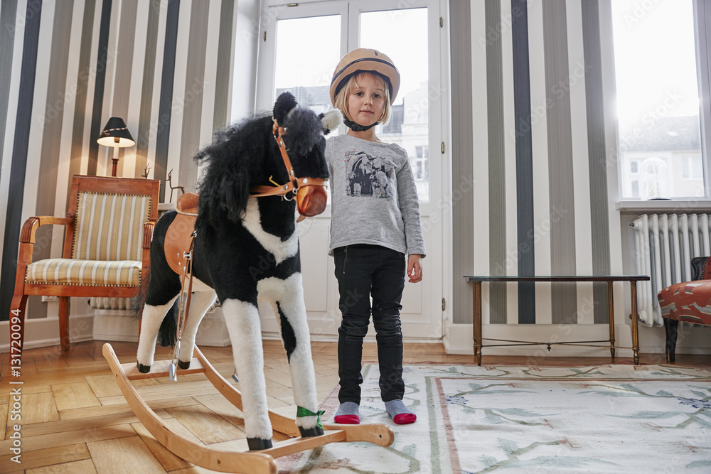 Girl standing next to rocking horse Stock Photo | Adobe Stock