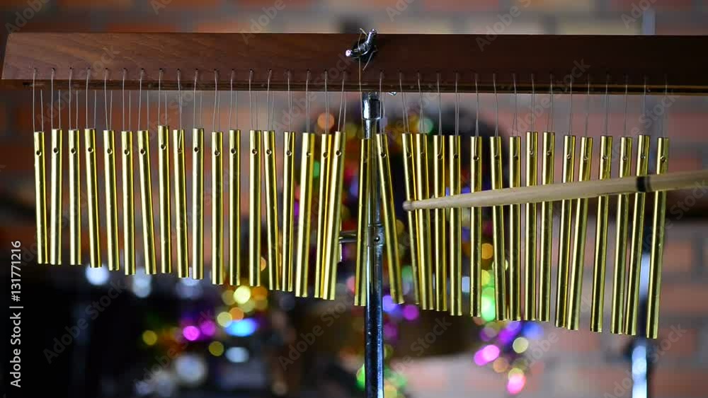 Man hand sweeping a stick through the length of the hanging bar chimes ...