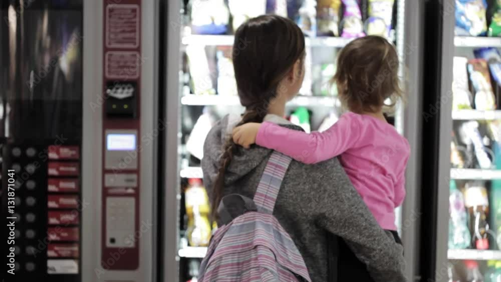 Mother and daughter selecting a snacks at vending machine inside ...
