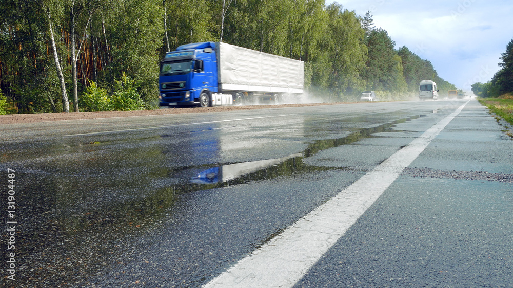View from ground of traffic on wet road, highway with mist splash after ...