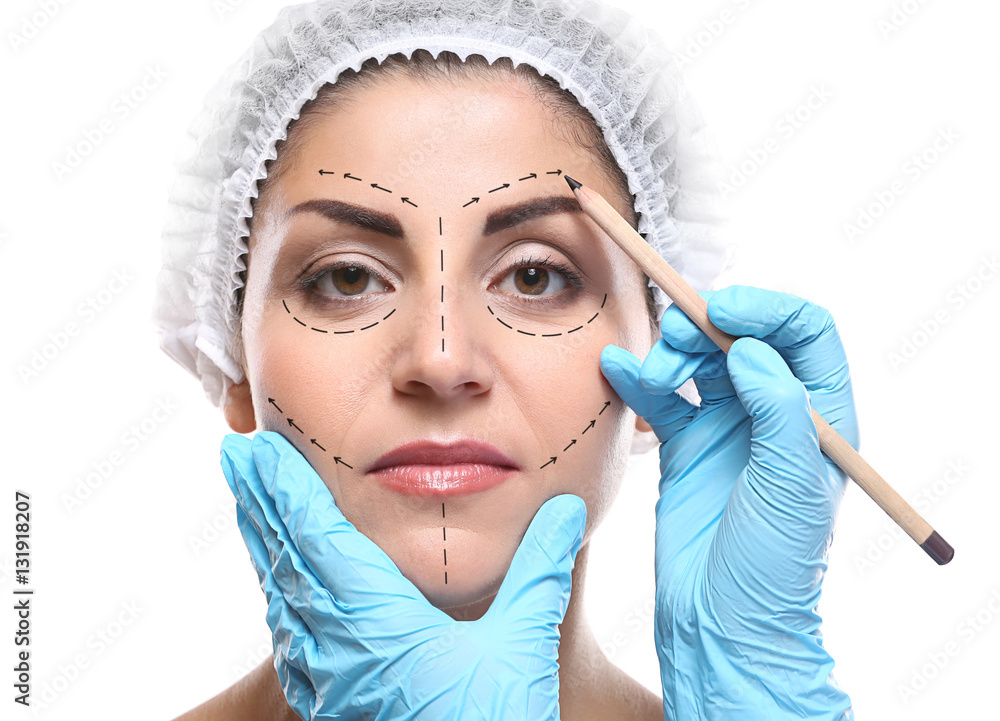 Surgeon drawing marks on female face against white background. Plastic ...