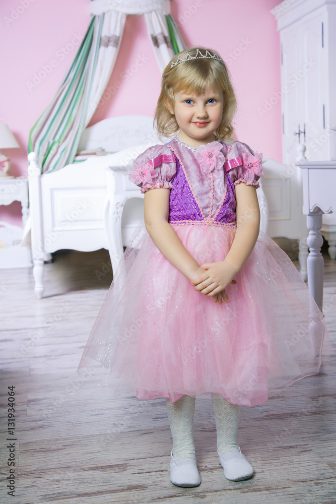 Little happy princess girl in pink dress and crown in her royal room ...