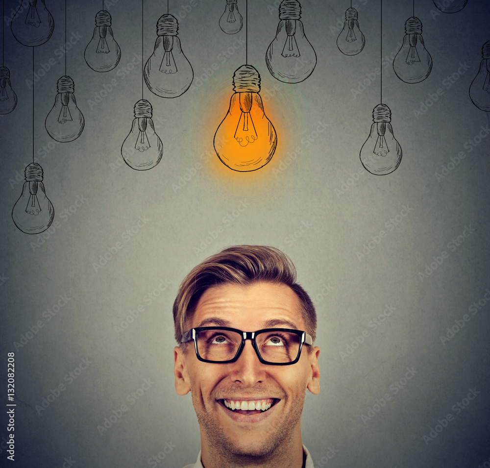 man in glasses looking up at bright idea light bulb above head Stock ...