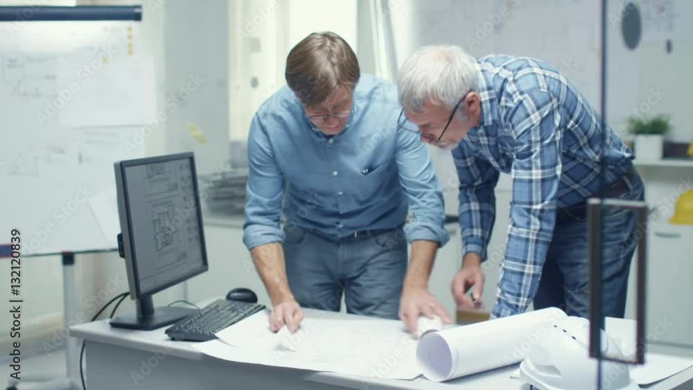 Two Senior Engineers Work with Schemes and Plans Standing over Working ...