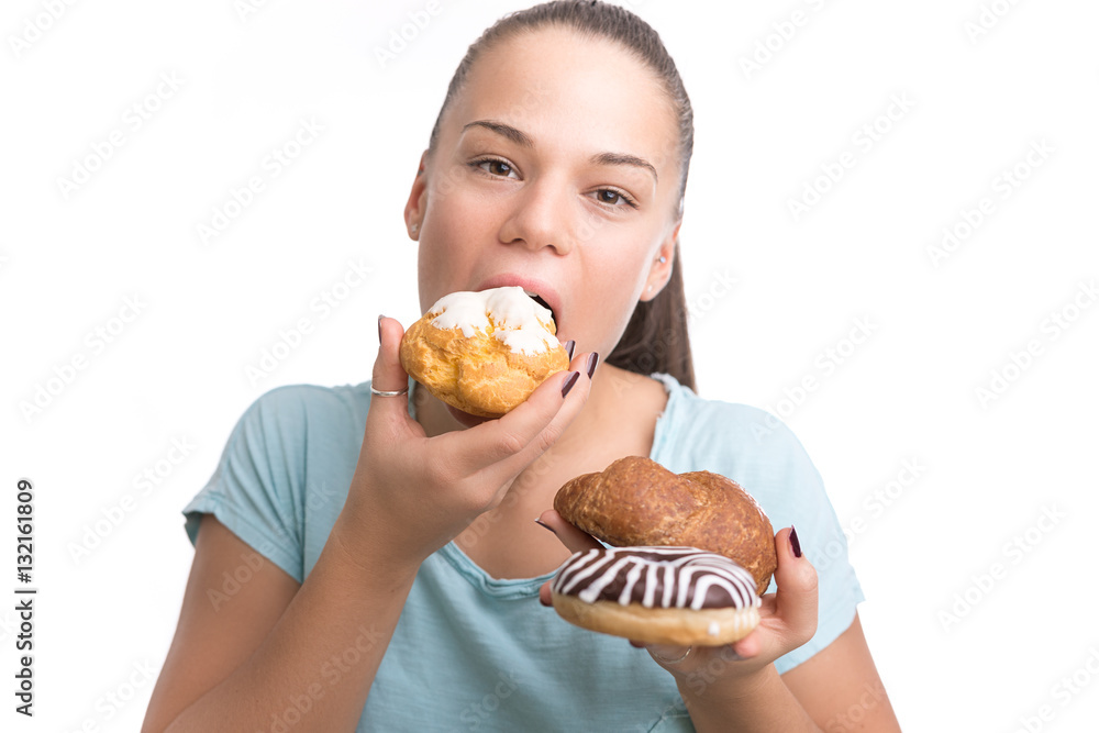 Young happy brunette girl eating a big cream puff over white background ...