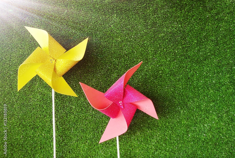 Pink and yellow pinwheels on the green grass background. Picture with ...