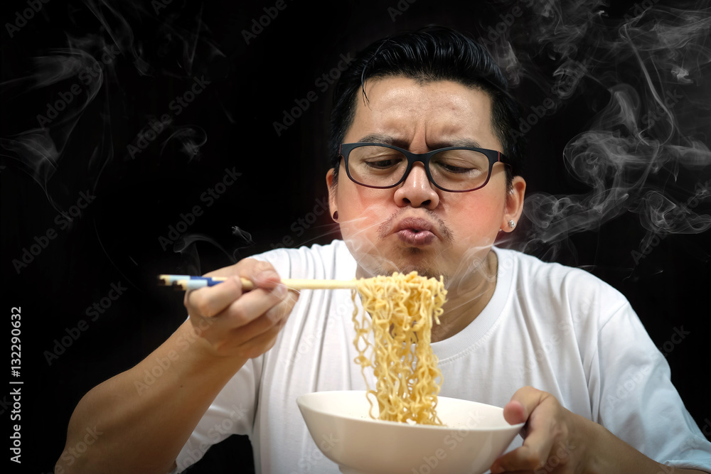 Asian man eating Instant noodles very hot and spicy on black background ...