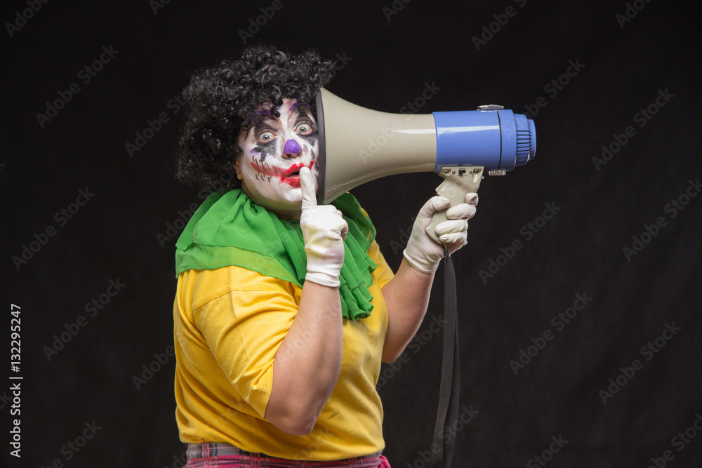 Scary clown shouting into a megaphone on a black background Stock Photo ...