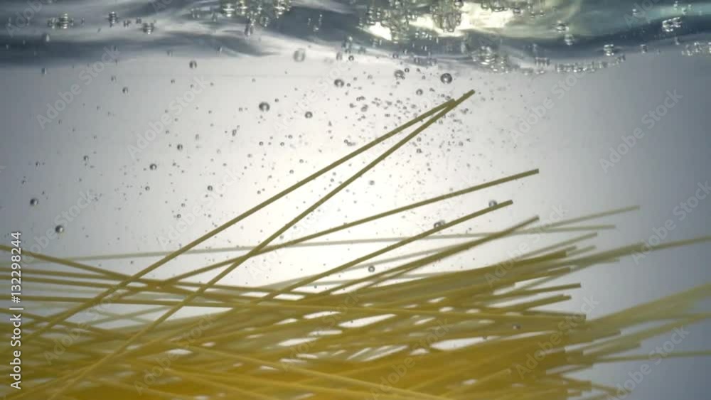 Spaghetti falling into water. Shooting from the water bottom. Slow ...