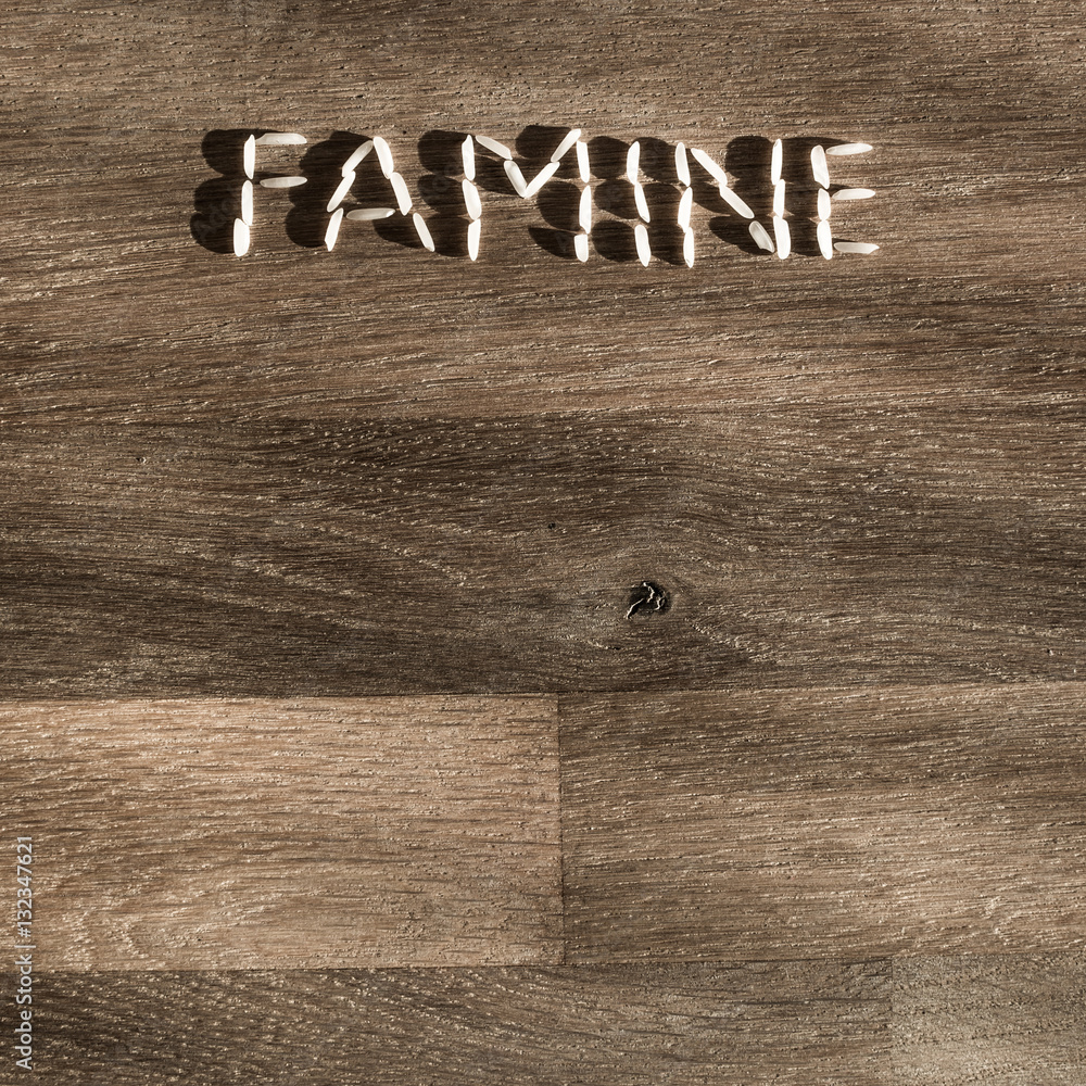Word famine made of few white rice grains on wooden table - symbol of ...