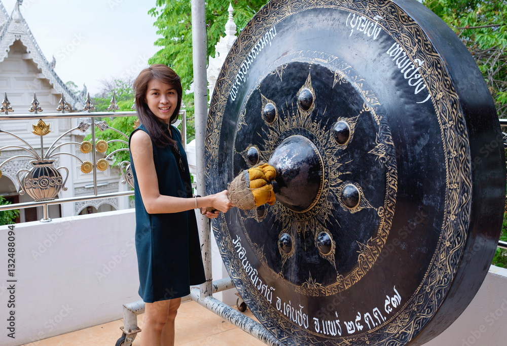 thai young adult woman hold wooden hammer to hit big circle bell in ...