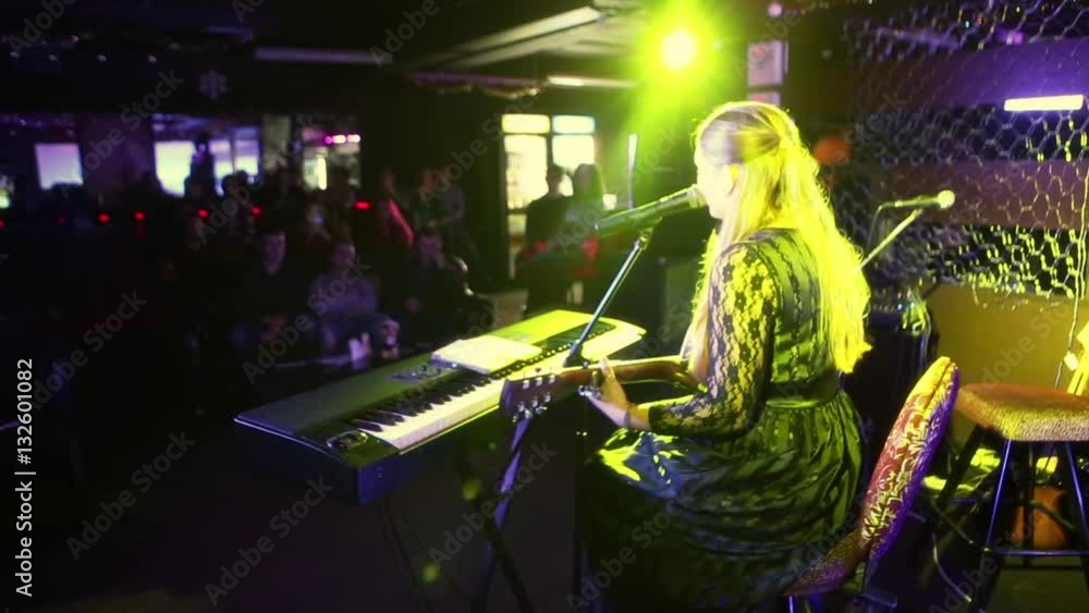 Girl on stage with a guitar. Concert rock band performing on stage with ...