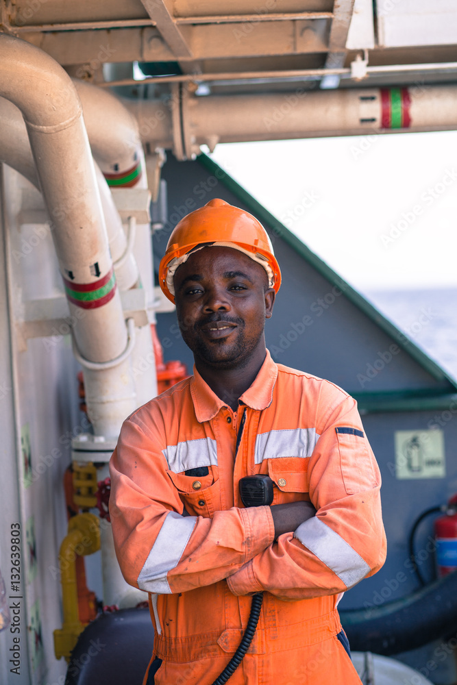 young african seaman standing on deck dressed in coverall and safety ...