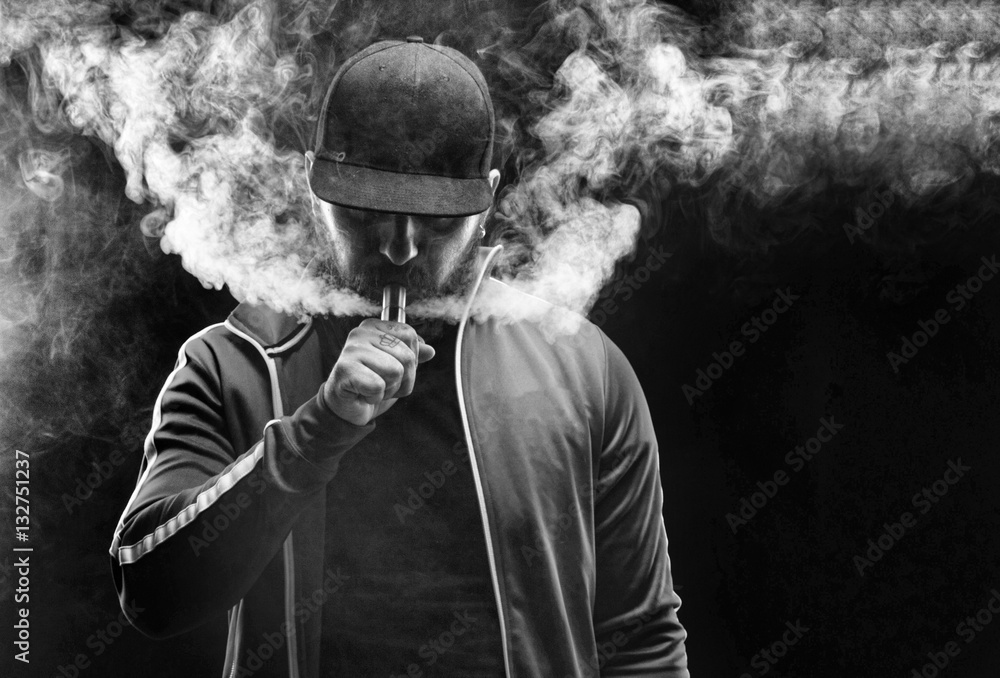 vaping man holding a mod. A cloud of vapor. Black background Stock ...