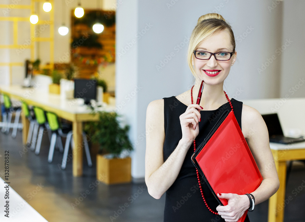 Cheerful pretty girl assistant holds in hands a pen and folders in an ...