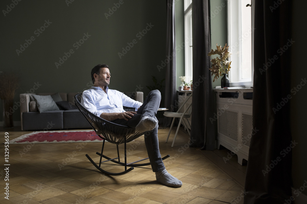 Man sitting on rocking chair in his living room looking through window ...