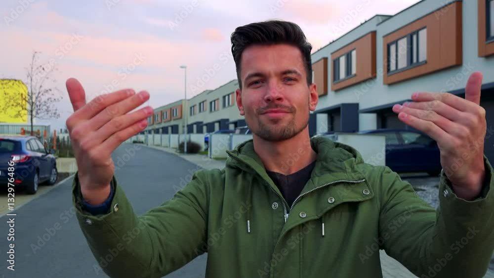 A young, handsome man invites you with gestures of his hands to look at ...