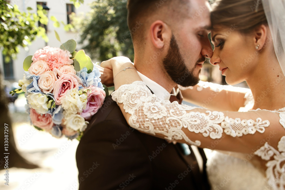 Peaceful bride holds her arms on groom's shoulders while he hugs Stock ...