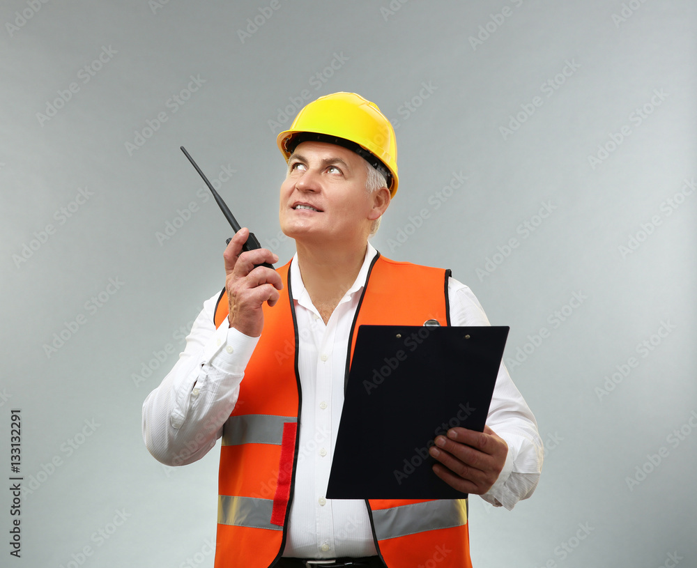 Senior engineer with portable radio transmitter and clipboard on light ...