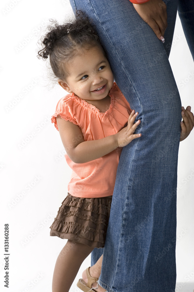 Little girl hiding behind the saftey of her mothers leg. Stock Photo ...