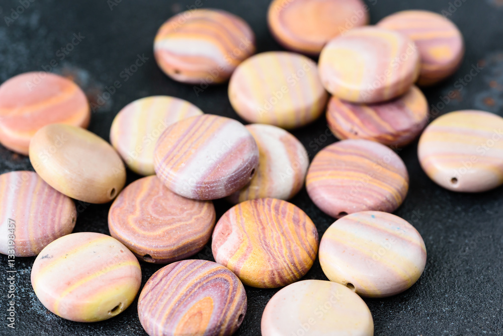Collection of multicolored coin shaped hickoryite beads on black cast ...
