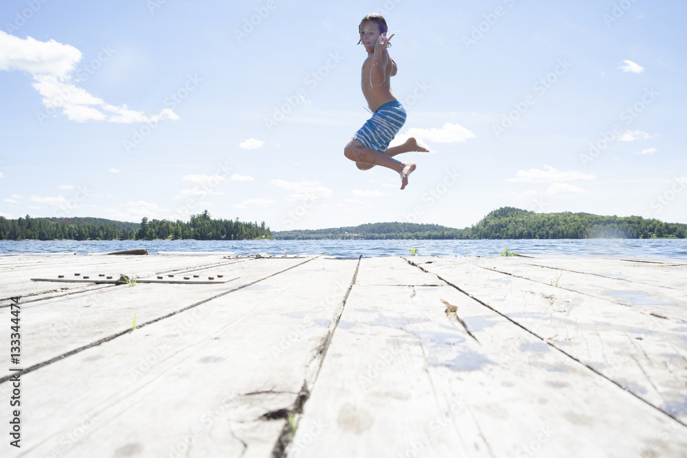 Pre Teen Boy Jumping Off Dock at Cottage Stock Photo | Adobe Stock