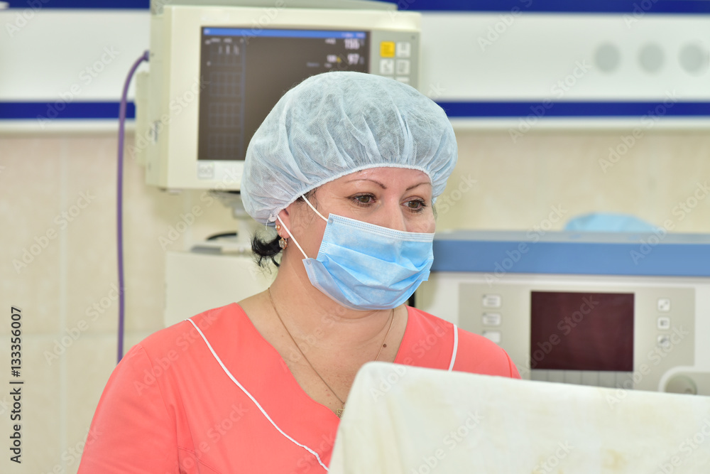 Nurse/The nurse looks at the monitor displaying the operation on the ...