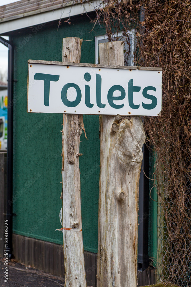Old toilet sign nailed to a tree trunk Stock Photo | Adobe Stock
