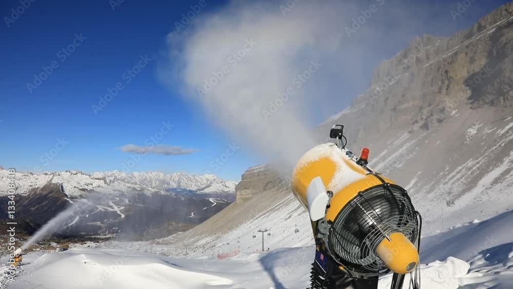 Yellow snow cannon stands on a snowy mountain in the winter and works ...