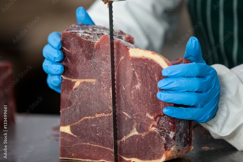 Female butcher cutting raw meat on a band saw machine Stock Photo ...