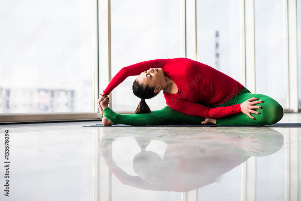 Djanu-shirasana. Beautiful yoga woman practice in a big window hall ...
