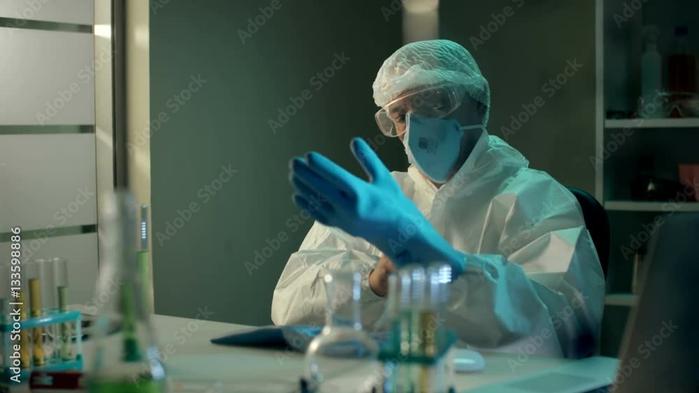 Scientist man in respirator putting on protective gloves before ...
