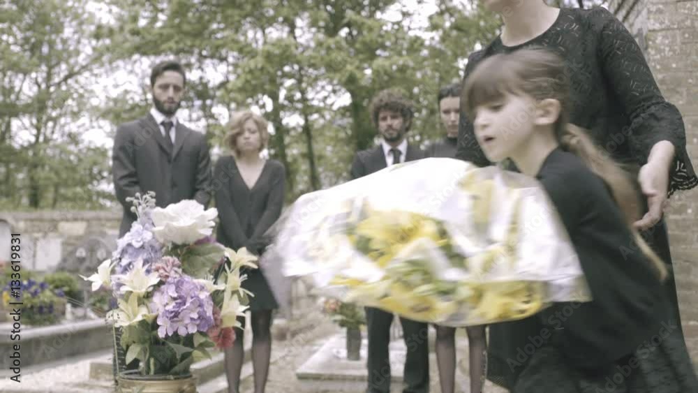 Mother and daughter laying flowers on grave Stock Video | Adobe Stock