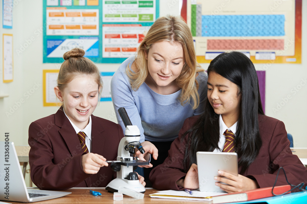 Teacher With Female Students Using Microscope In Science Class Stock ...