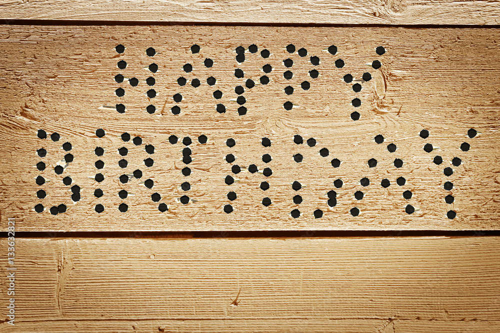 Happy Birthday congratulation made as text of bullet holes in wooden ...