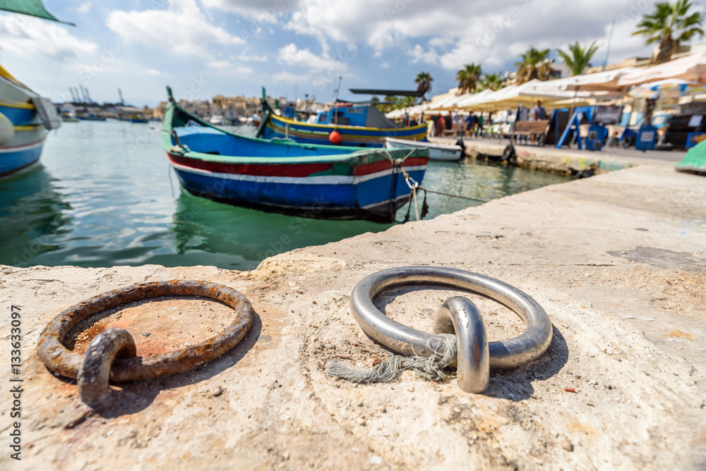 Mooring rings in Maltese harbor with traditional fishing boats in ...
