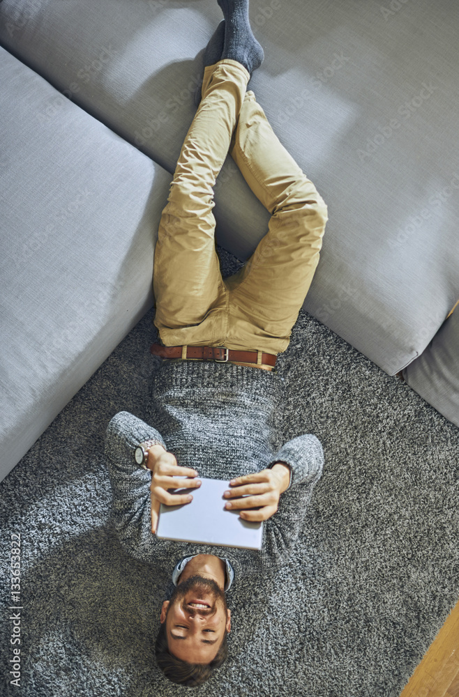 Man laying on floor with a tablet in his hands Stock Photo | Adobe Stock