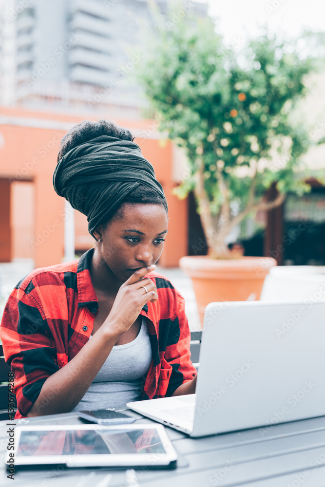 Young beautiful black woman sitting using a computer, tapping on the ...